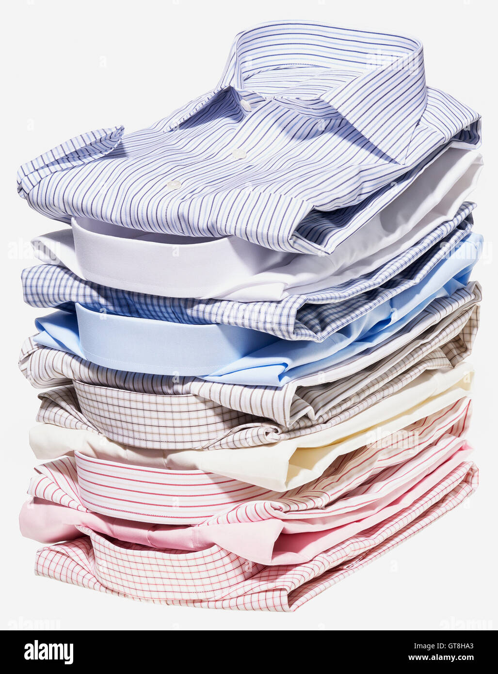 Stack of different coloured shirts on white background Stock Photo - Alamy