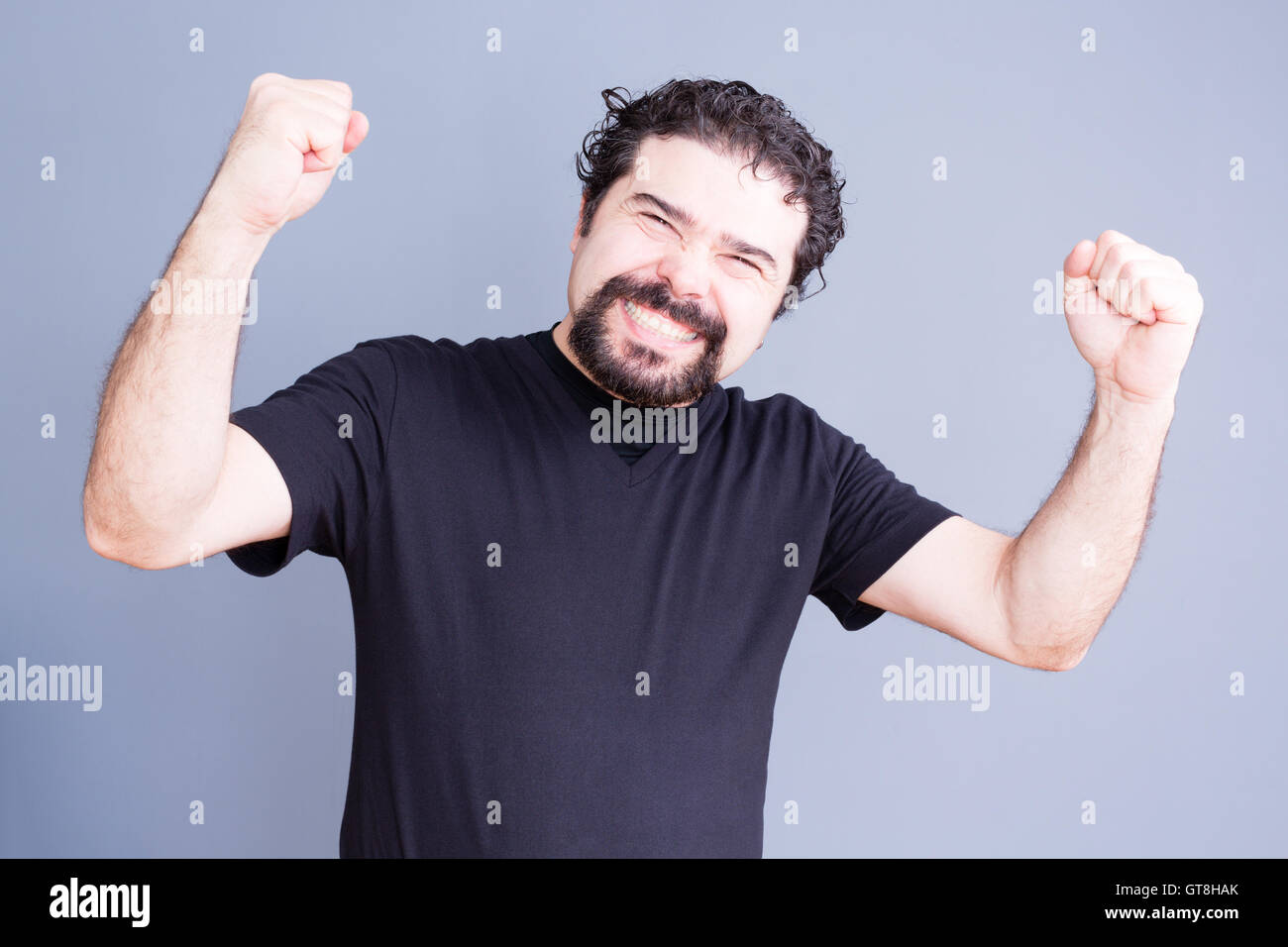 Single handsome bearded man in black shirt holding fists up with elated ...