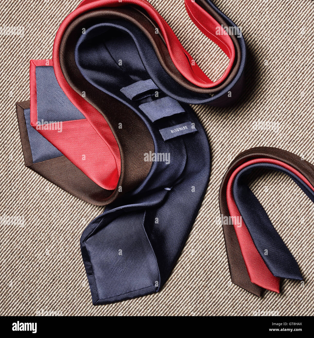Three coloured neckties draped on a light brown fabric Stock Photo - Alamy