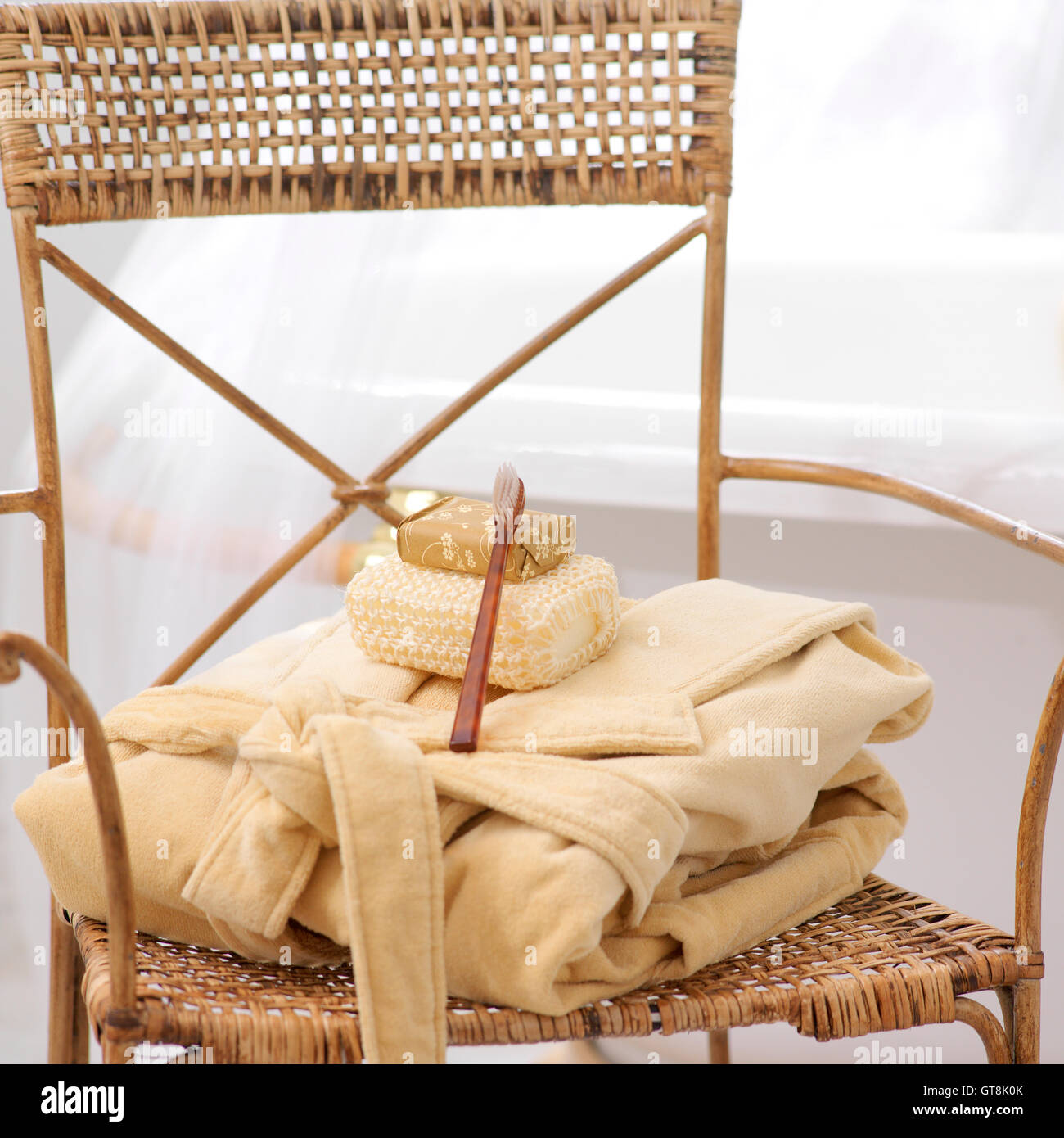 Folded Robe with Soap, Loofah and Toothbrush on Wicker Chair Stock ...