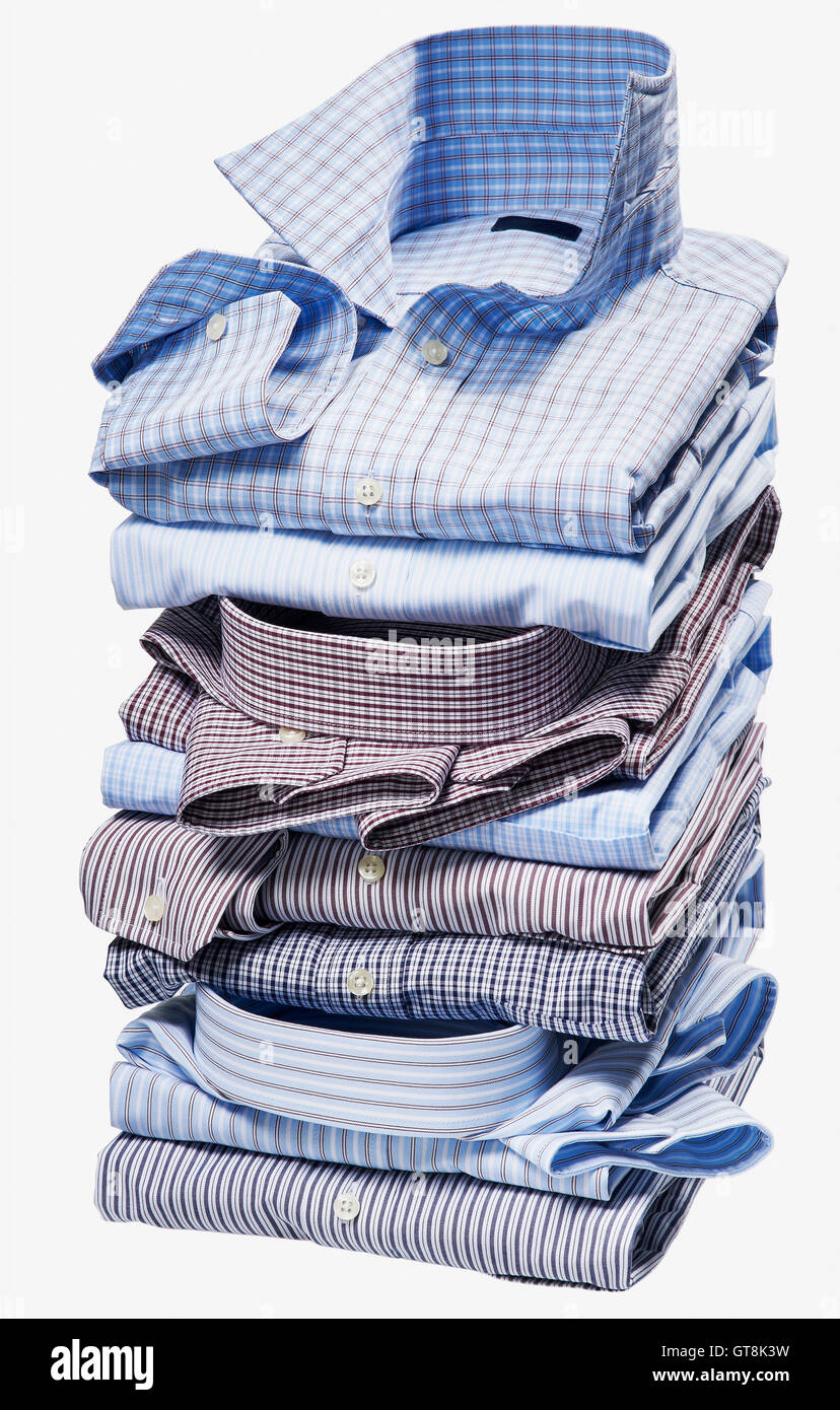 Stack of multi coloured checked and striped shirts on white background ...