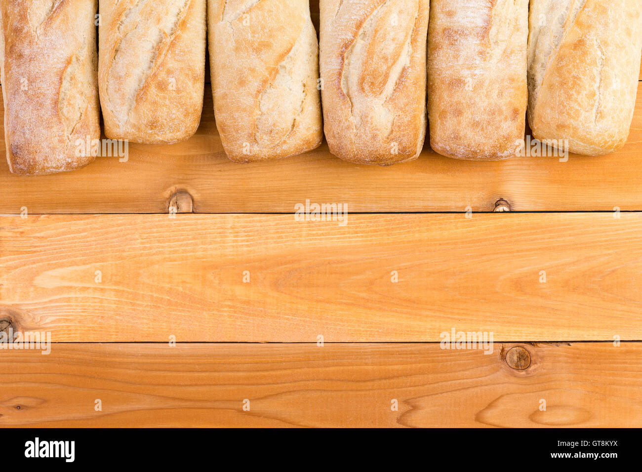 Crusty fresh bread loaf border arranged in a line on a wood background ...