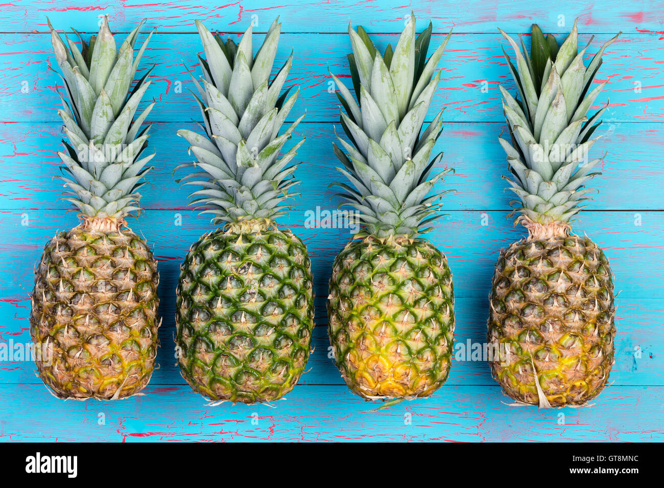 Four large ripe pineapple fruits arranged next to each other on old ...