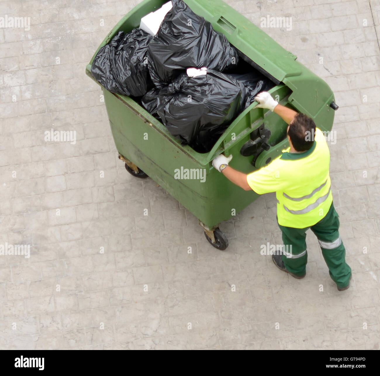 Man from city service pulling garbage bin Stock Photo - Alamy