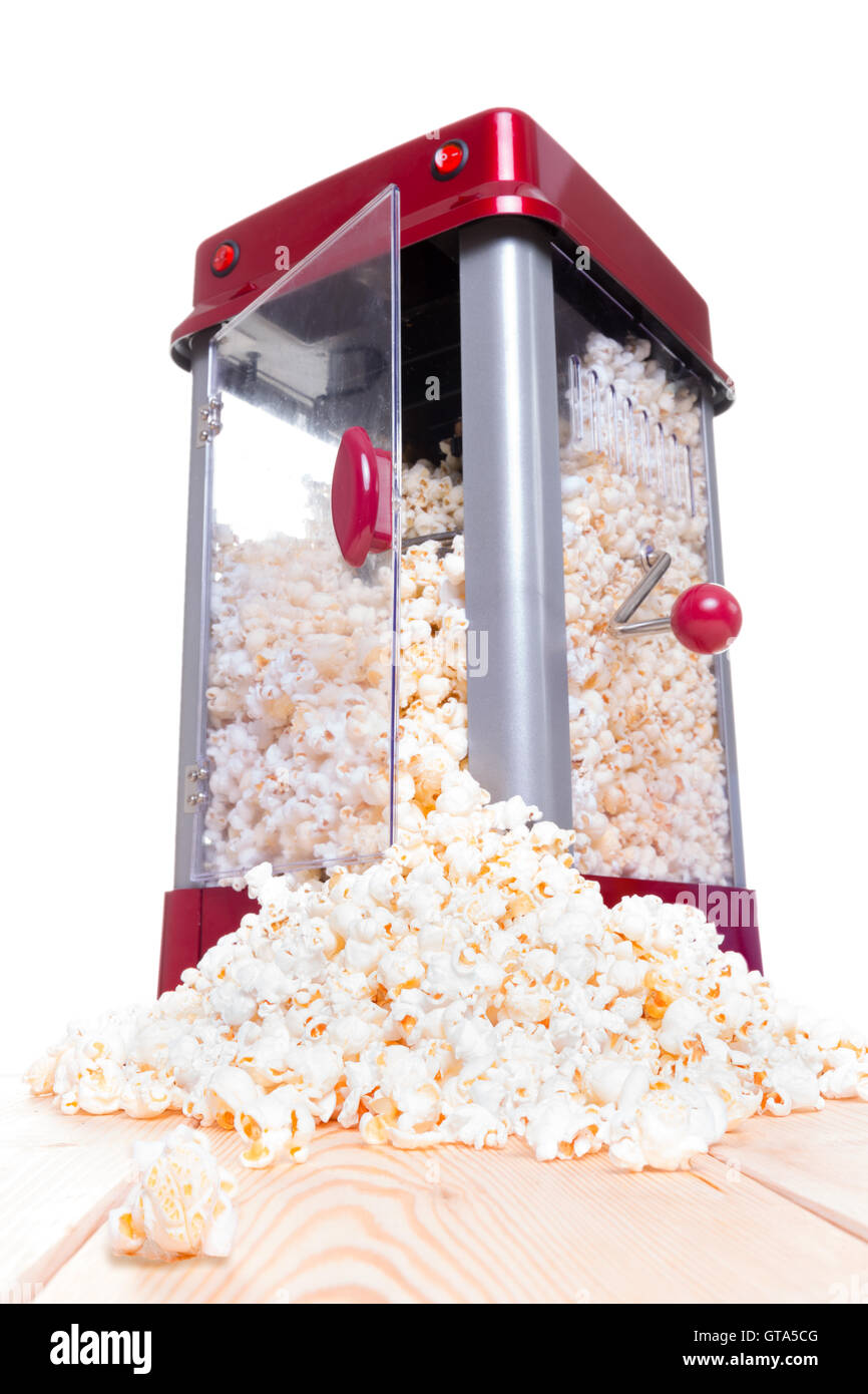 Open door of red and gray popcorn popper with food pouring out on light ...