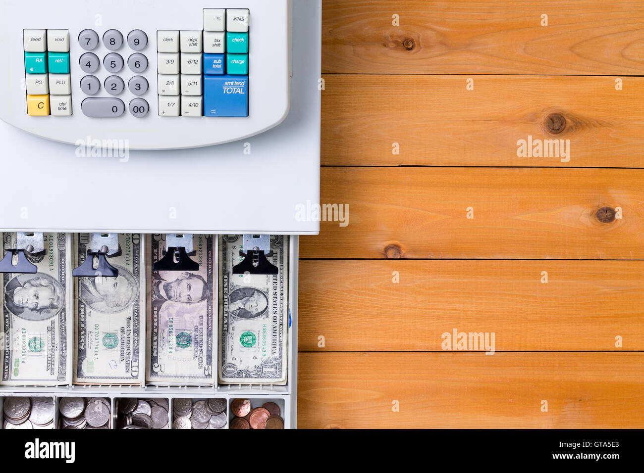 Top down view of cash register full of coins and bills over wooden ...