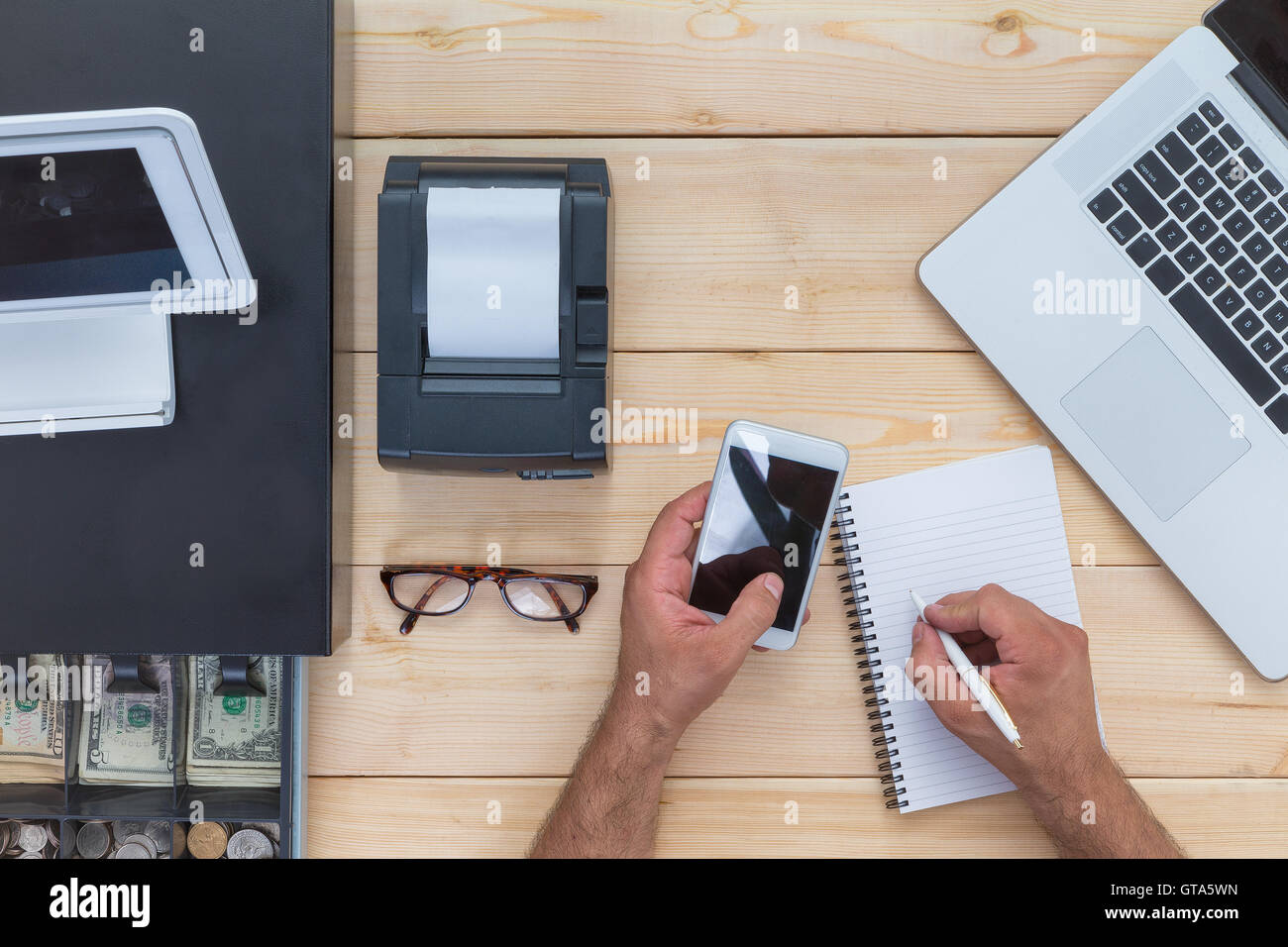 Businessman calculating his business cash flow seated at a desk with an ...