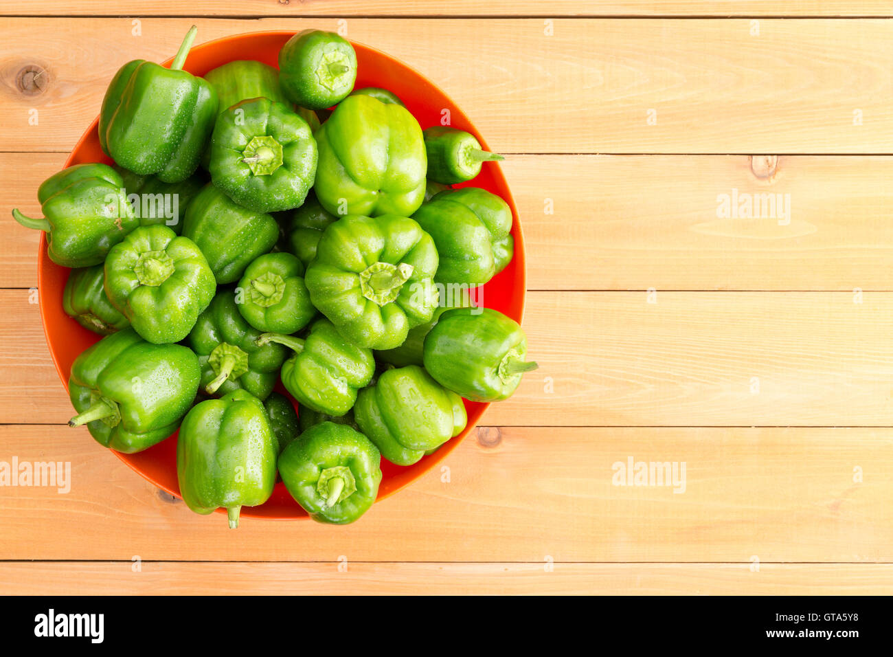 Overhead view of large red bowl filled beautiful fresh green peppers ...