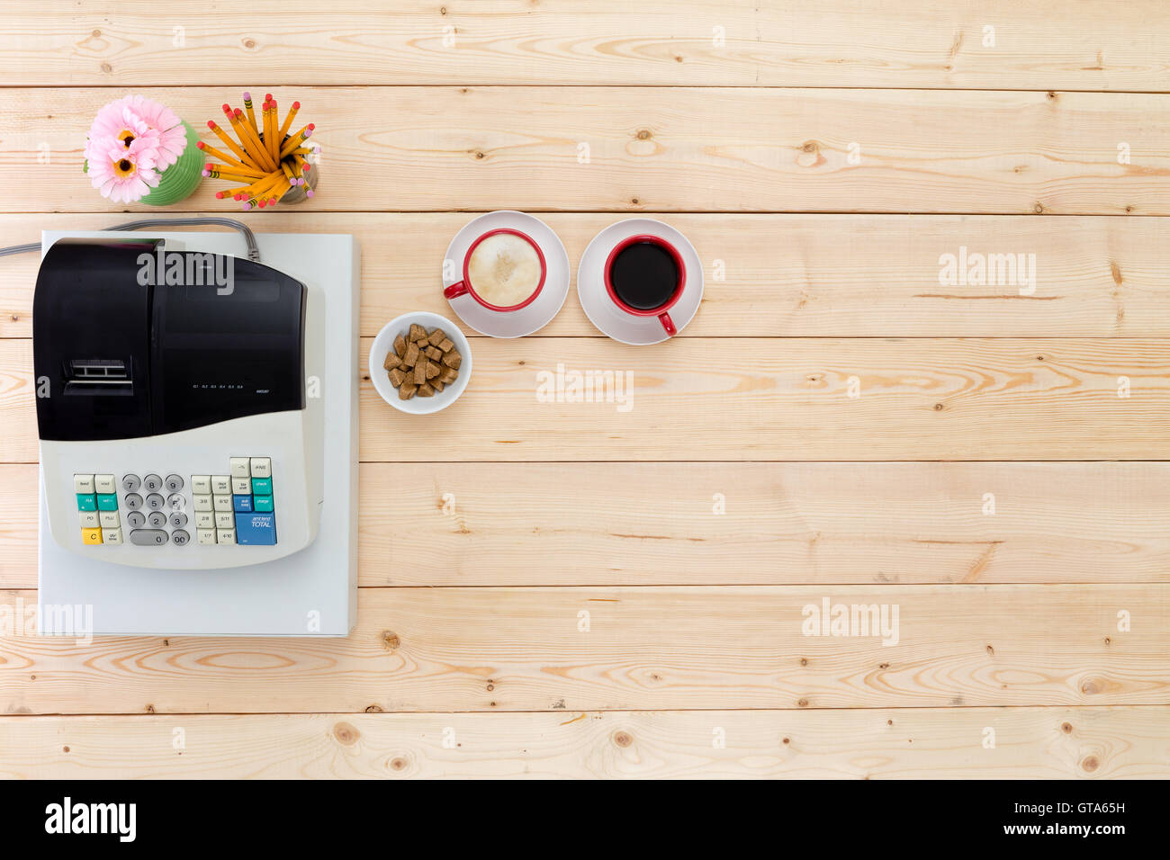 Two cups of black coffee alongside a till or cash register in a ...