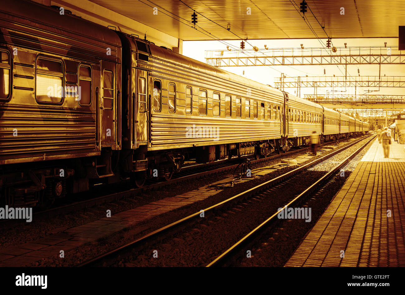 Train at railway station, sunset orange light Stock Photo - Alamy
