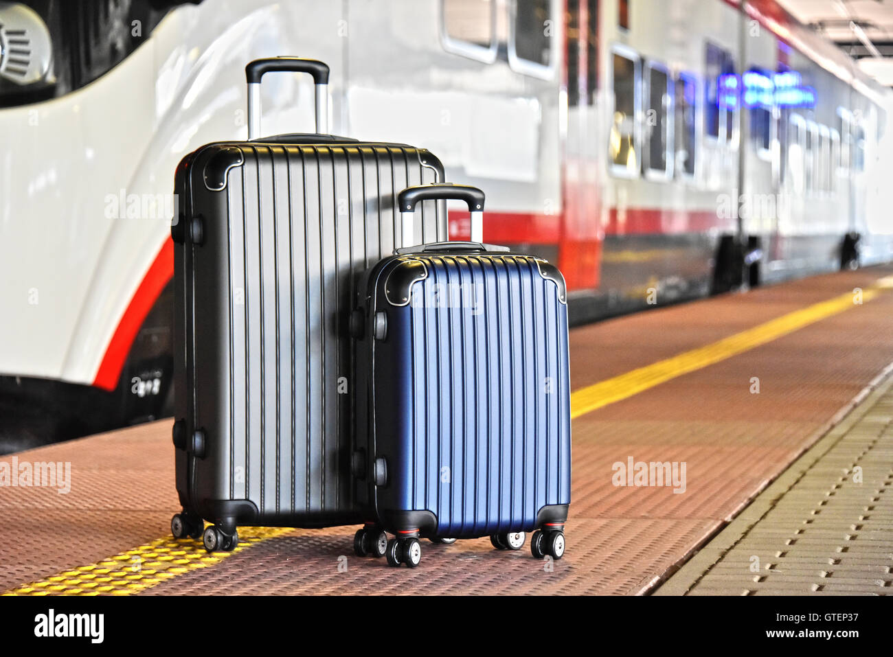 Two plastic travel suitcases on the railroad platform Stock Photo - Alamy