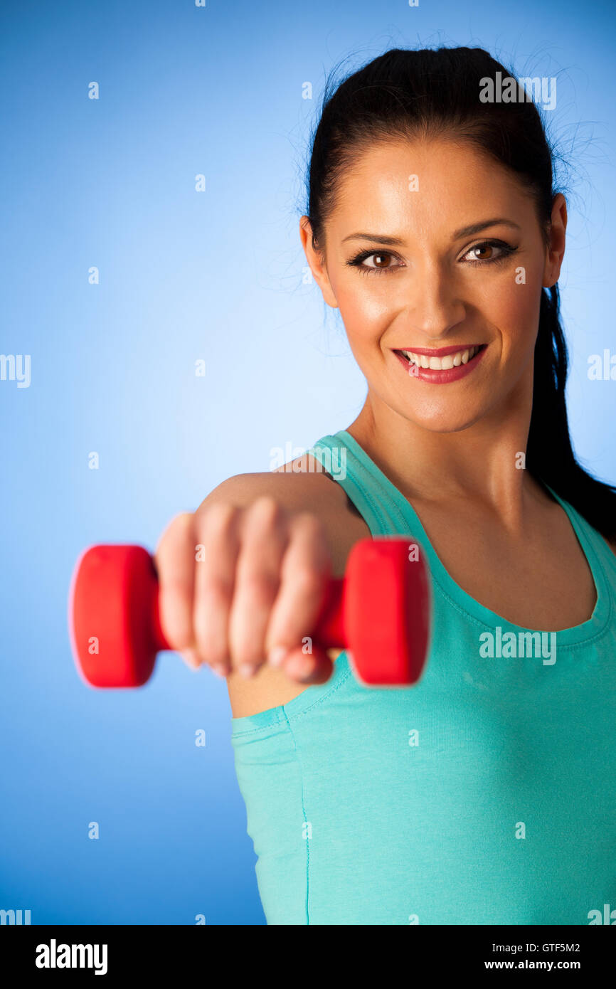 active woman with dumbbells workout in fitness gym over blue background ...