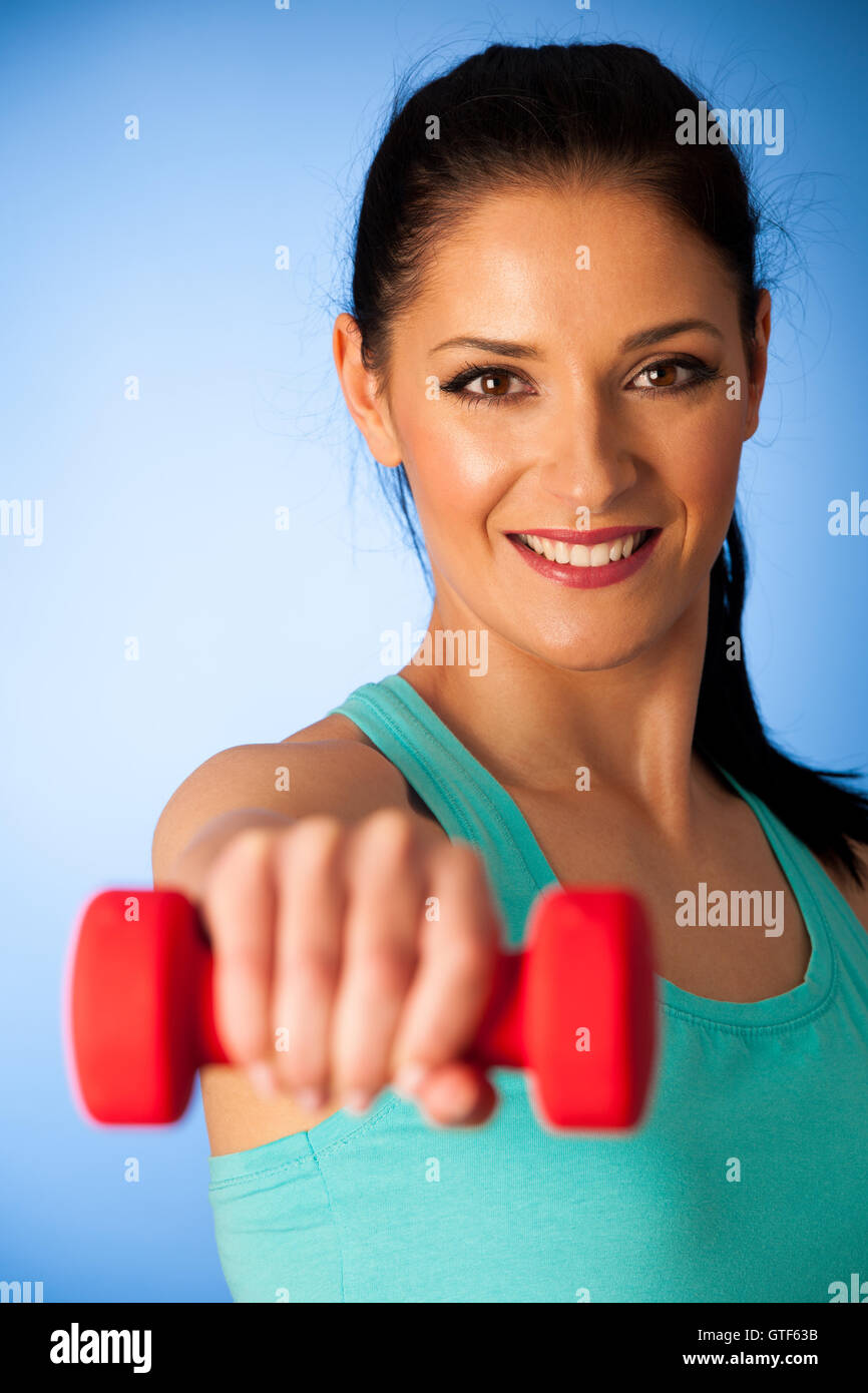 active woman with dumbbells workout in fitness gym over blue background ...
