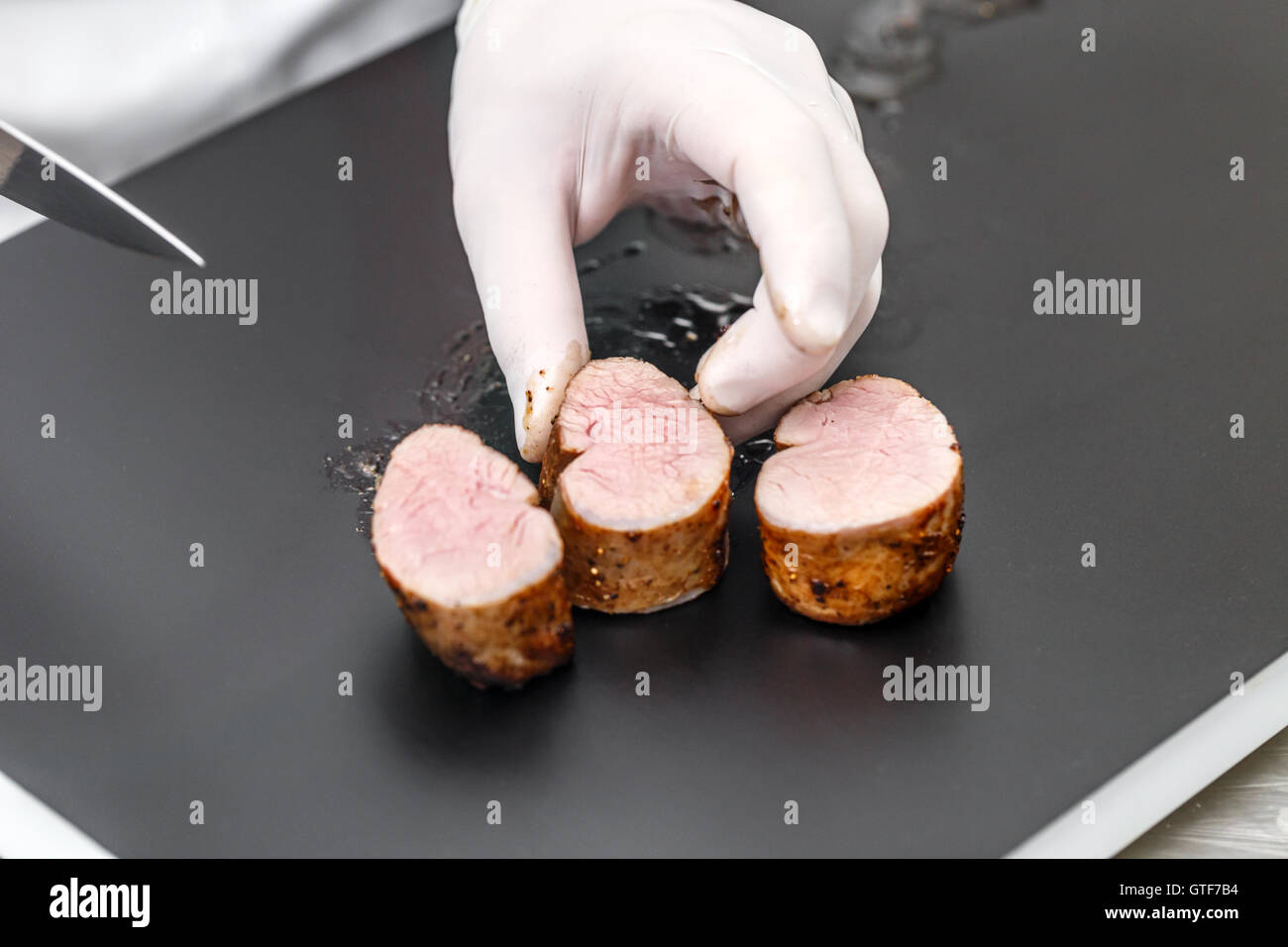 Chef in restaurant kitchen cutting meat for a dish Stock Photo - Alamy