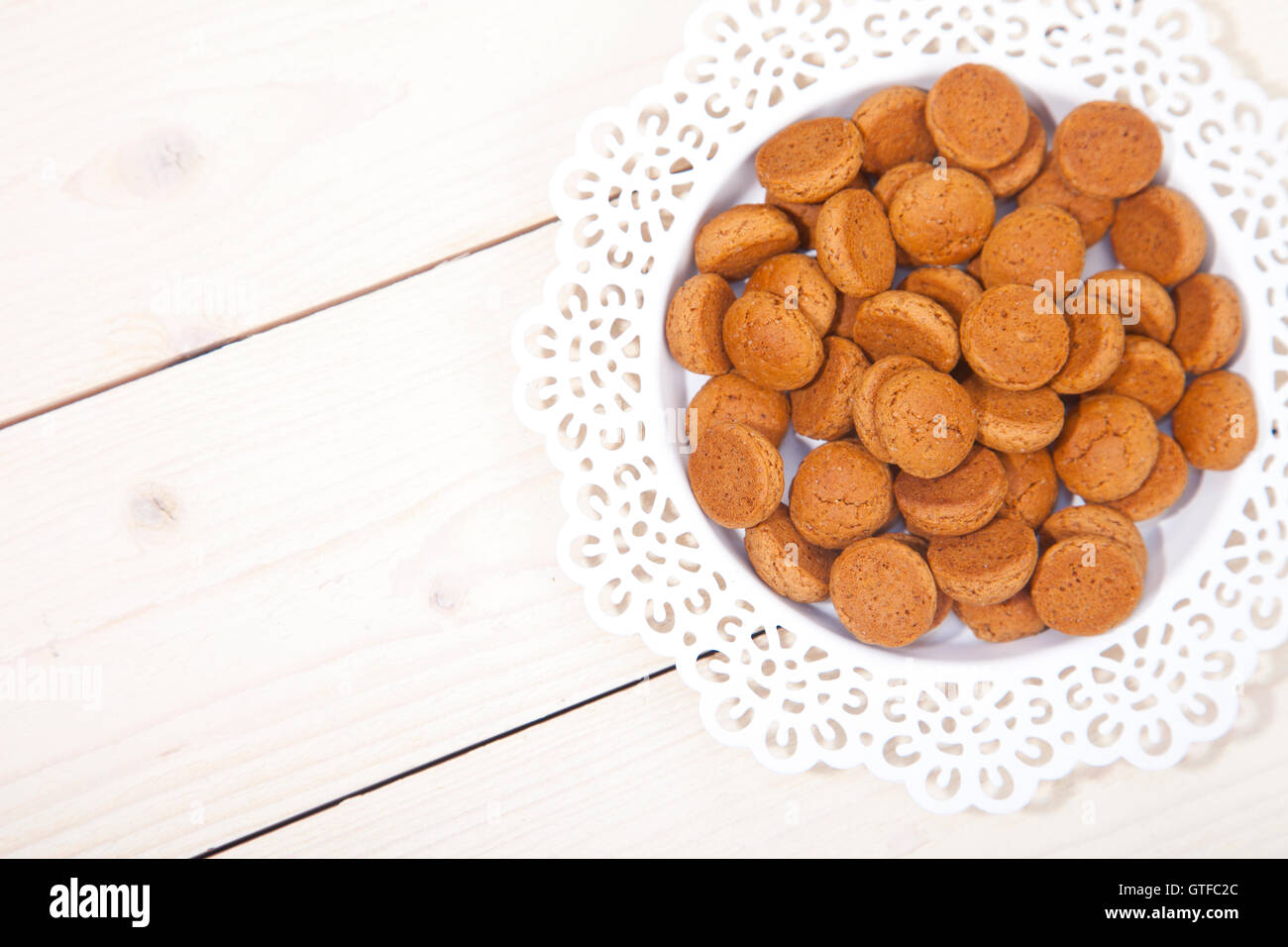 Traditional Dutch candy pepernoot on white plate on white wooden ...