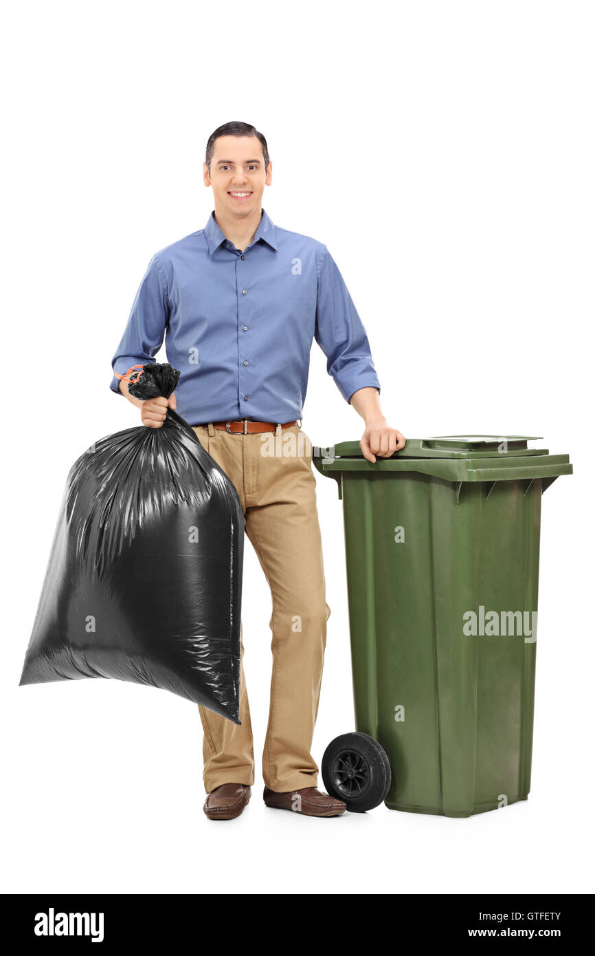 Young guy standing next to a garbage can and holding a trash bag ...