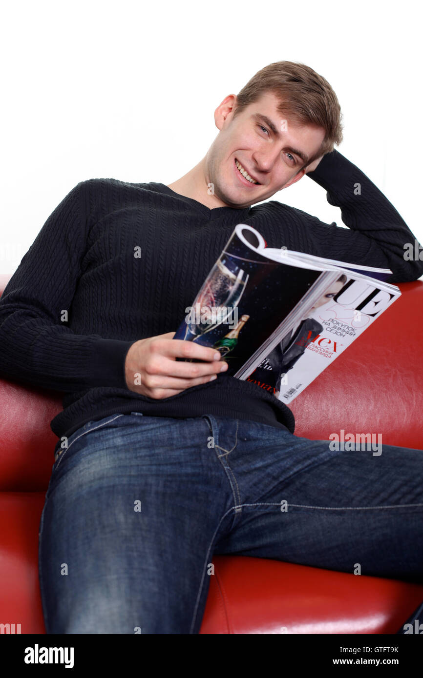 young man with magazine sitting on sofa Stock Photo - Alamy
