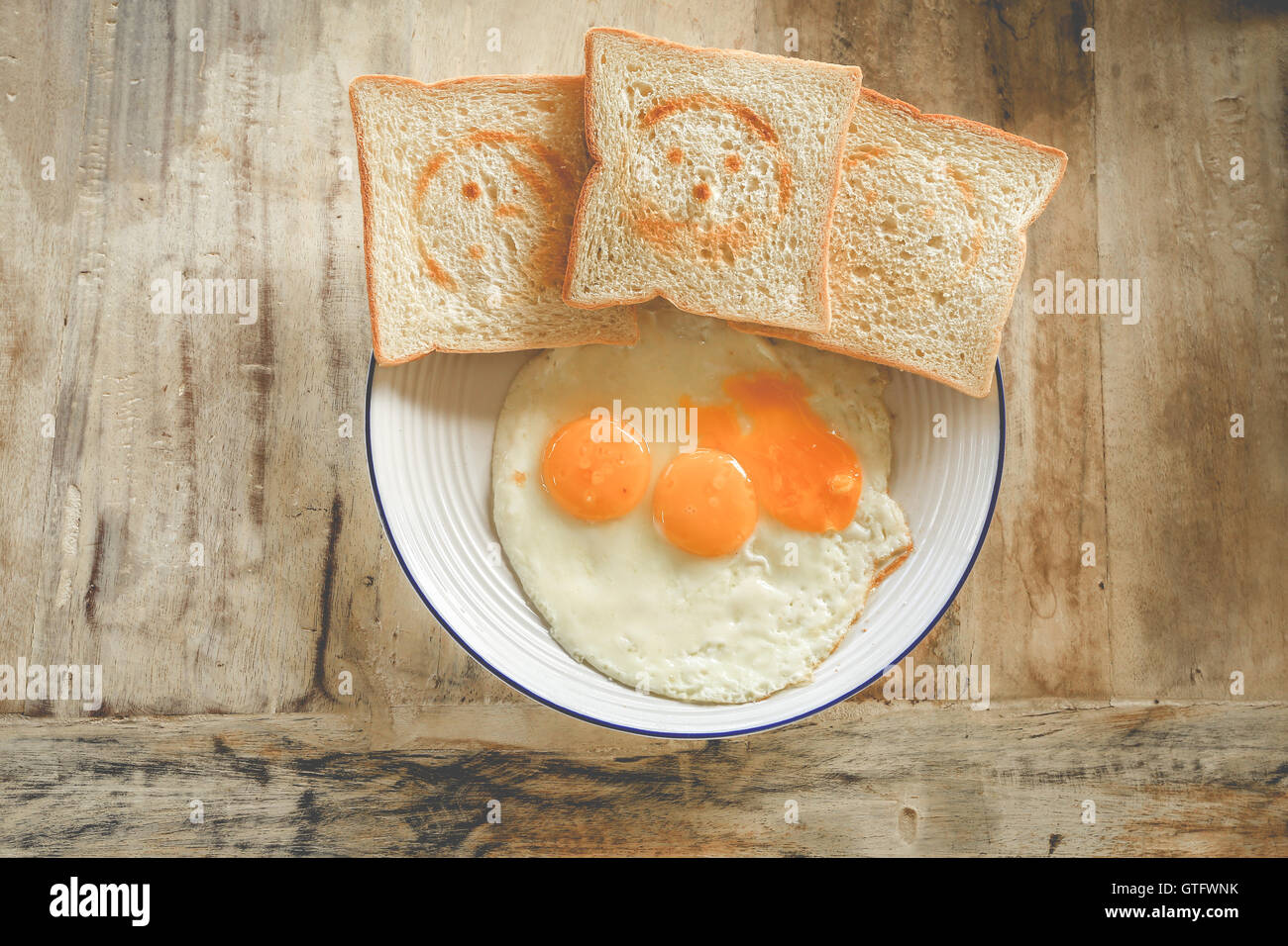 Wheat bread toasts with smiling stamp and fried eggs on wooden table ...