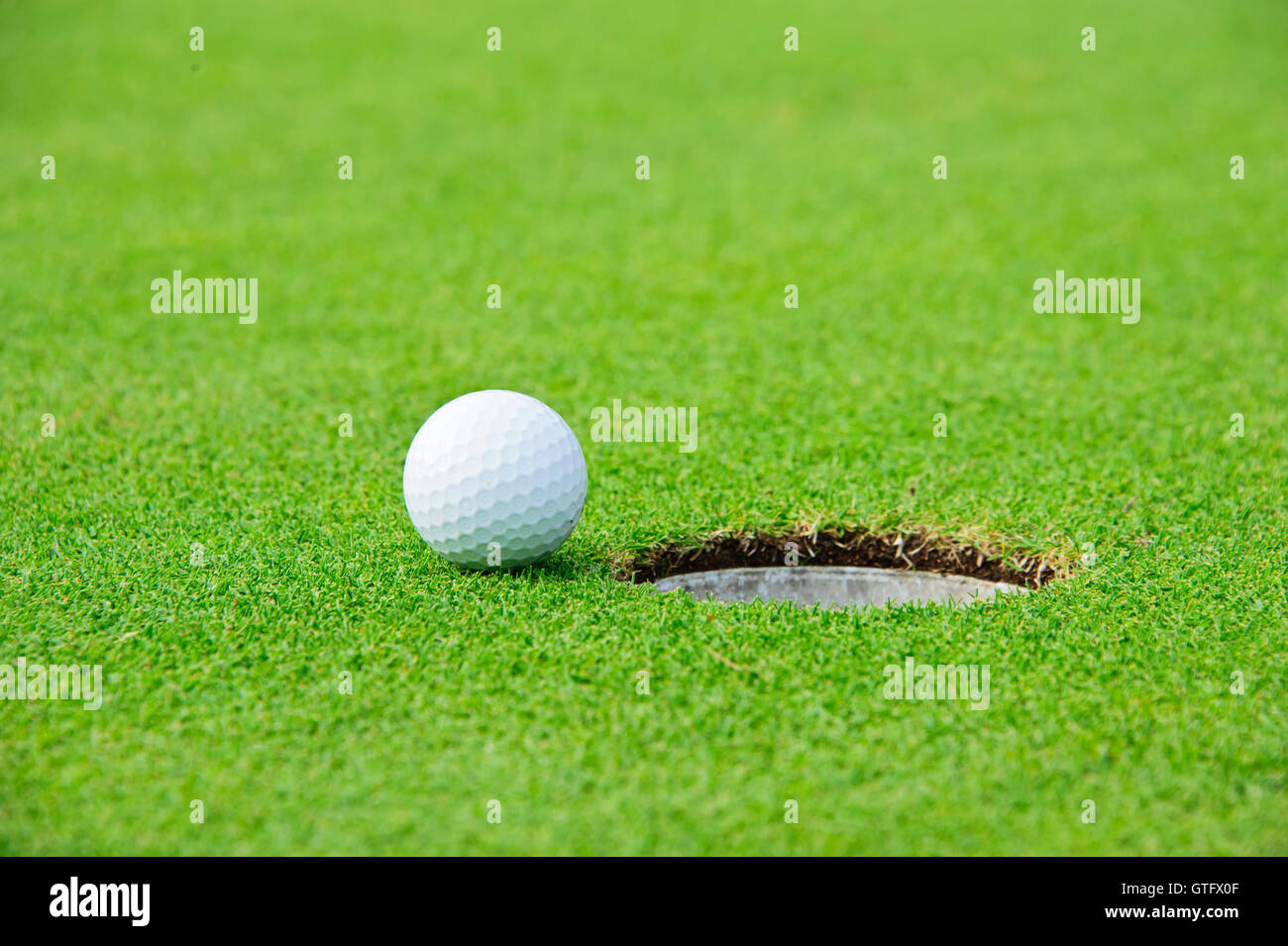 Golf Ball on Edge of Hole Stock Photo - Alamy