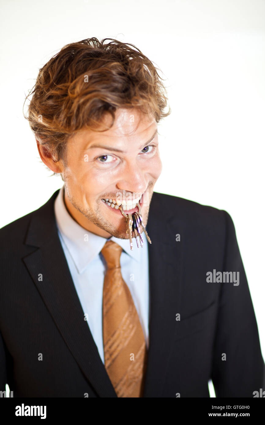 Smiling businessman holding keys between his teeth Stock Photo - Alamy