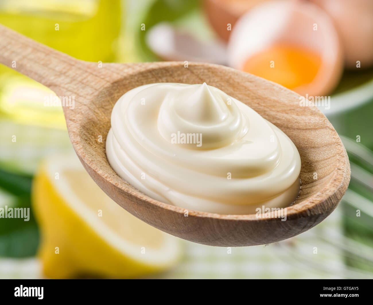 Natural mayonnaise sauce in the wooden spoon and its ingredient on the ...