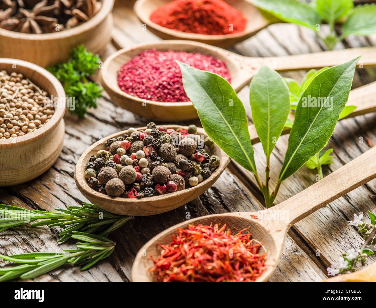 Assortment of colorful spices in the wooden spoons and herbs on the wooden table Stock Photo - Alamy