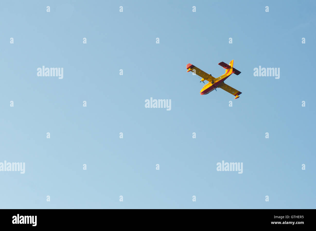 Yellow plane with red lines flying on clear blue sky Stock Photo - Alamy