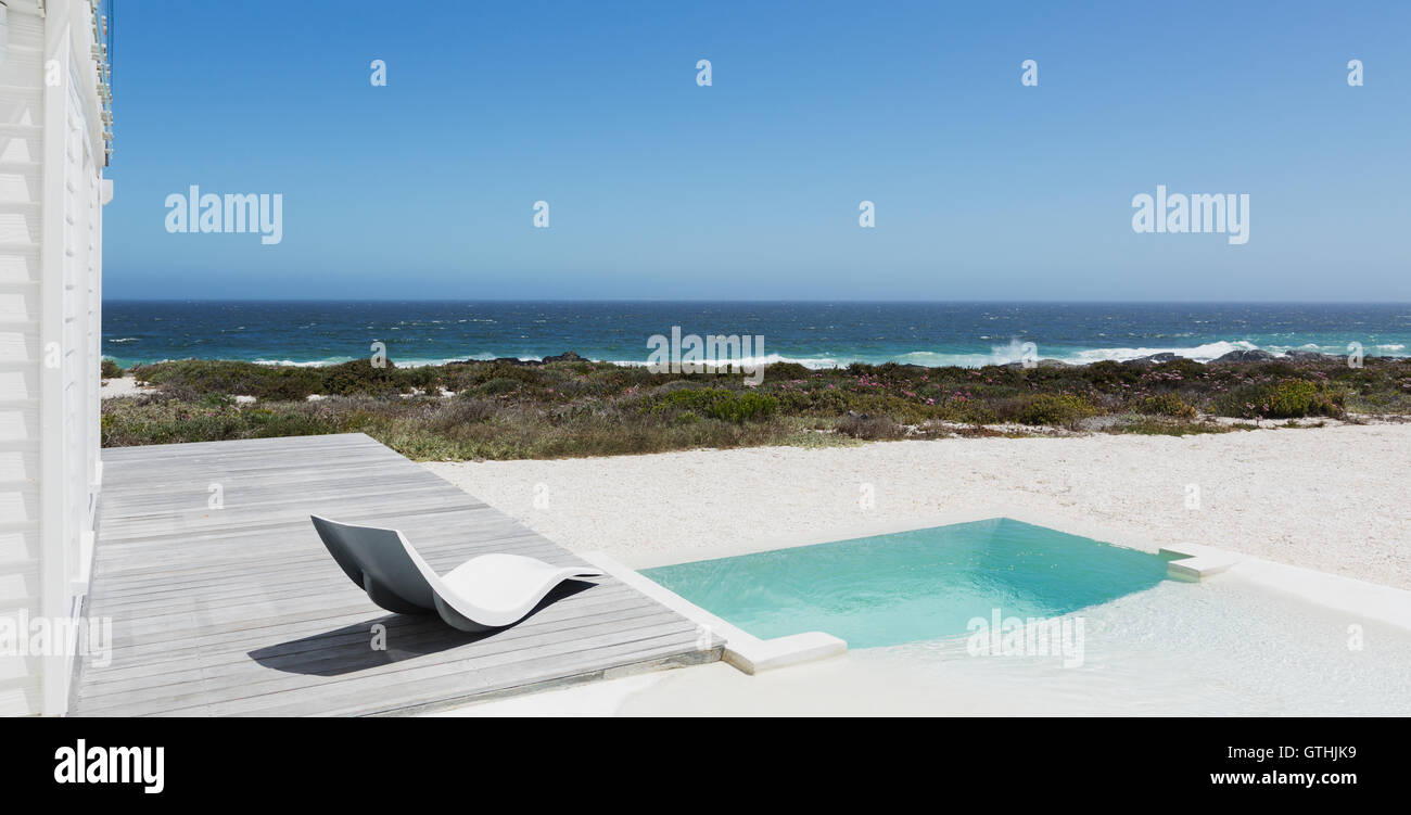 Soaking pool and modern lounge chair with ocean view under sunny blue ...