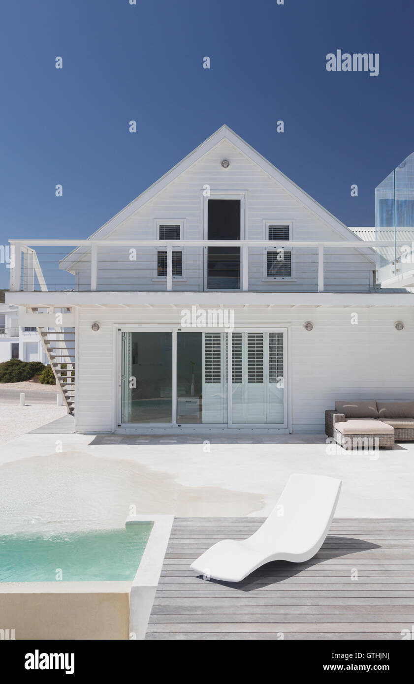 White house with swimming pool and modern lounge chair under sunny blue ...