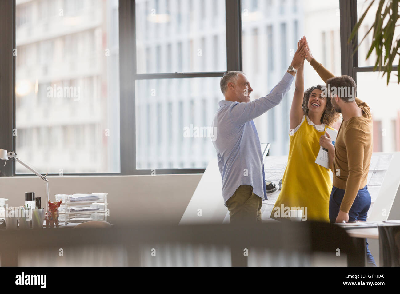 Architects high fiving in office Stock Photo - Alamy