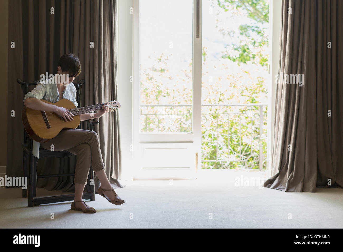 Woman playing guitar at balcony window Stock Photo - Alamy