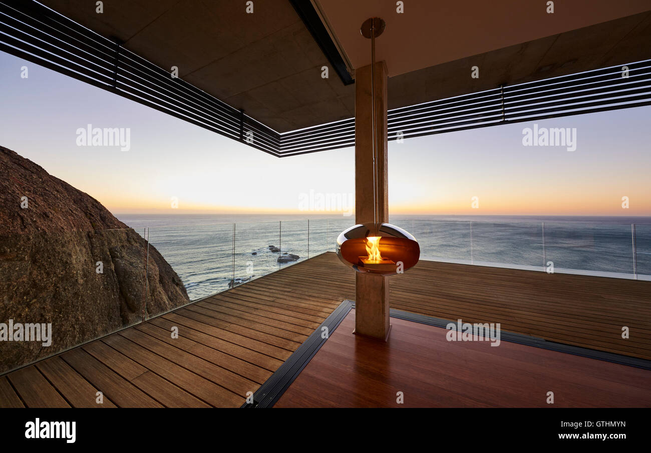 Modern hanging fireplace on luxury beach house patio with sunset ocean ...