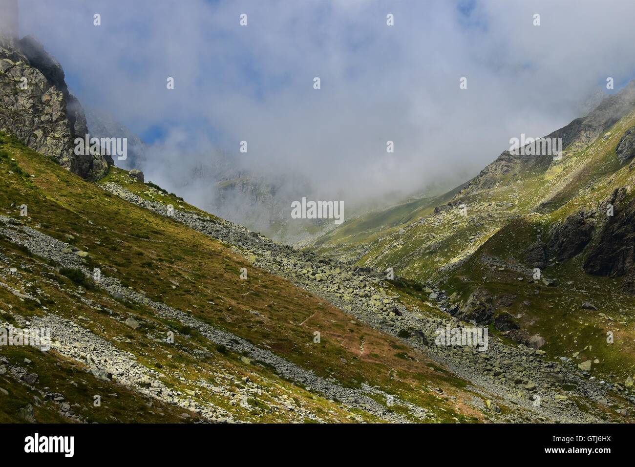 Beautiful mountains and valleys with steep rocks, paths and fog form ...