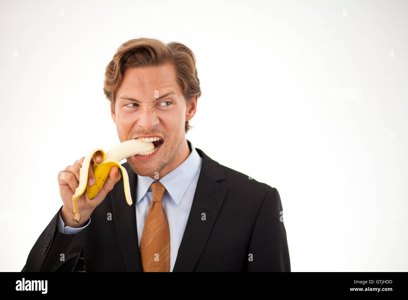 Suspicious businessman eating banana Stock Photo - Alamy