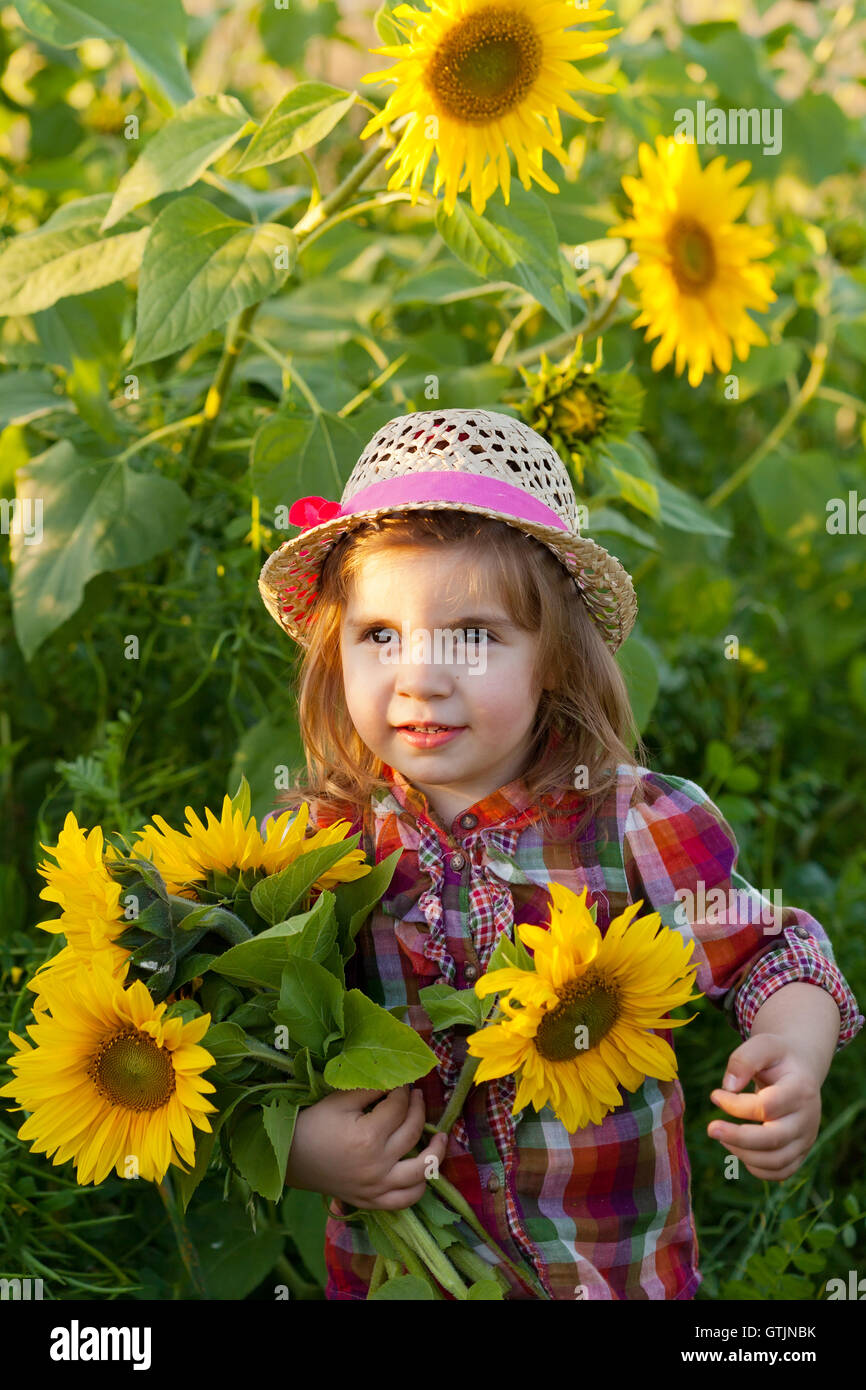 Little girl in a summer hat among sunflowers Stock Photo - Alamy