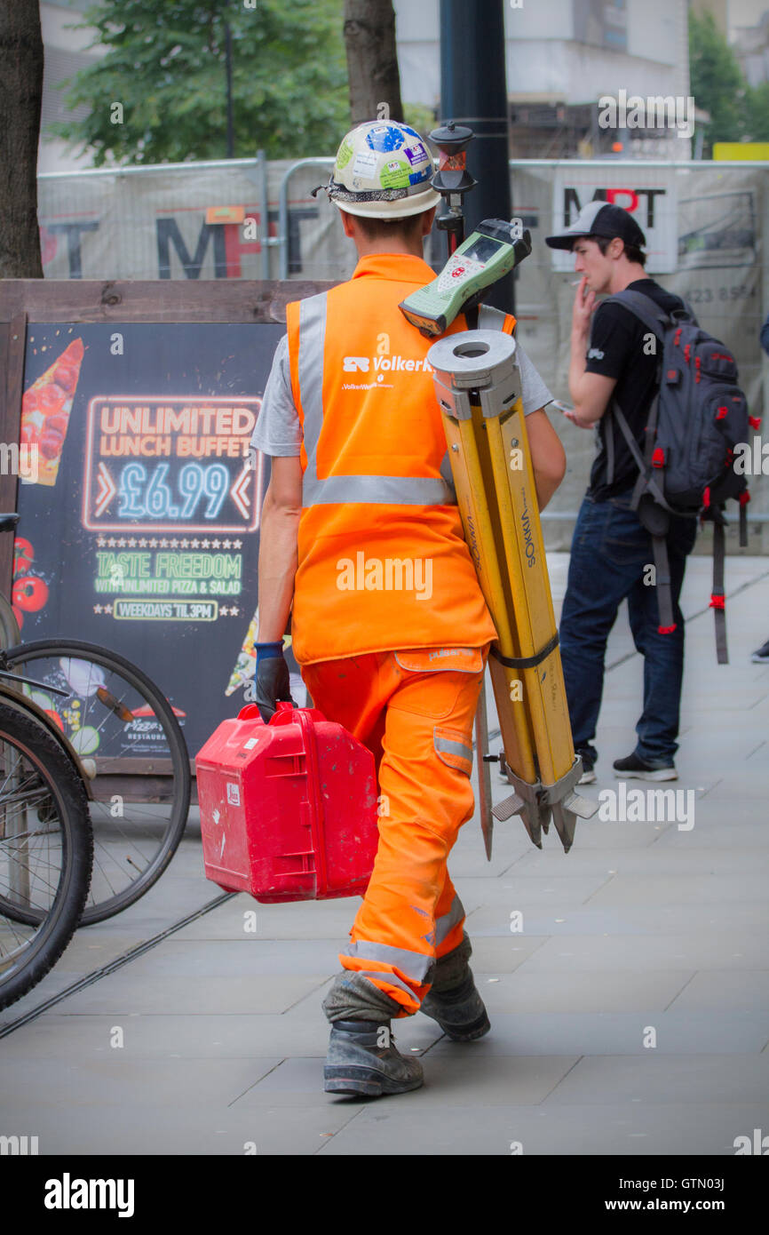 A workman carrying theodolite & carry case, Manchester, UK Stock Photo ...