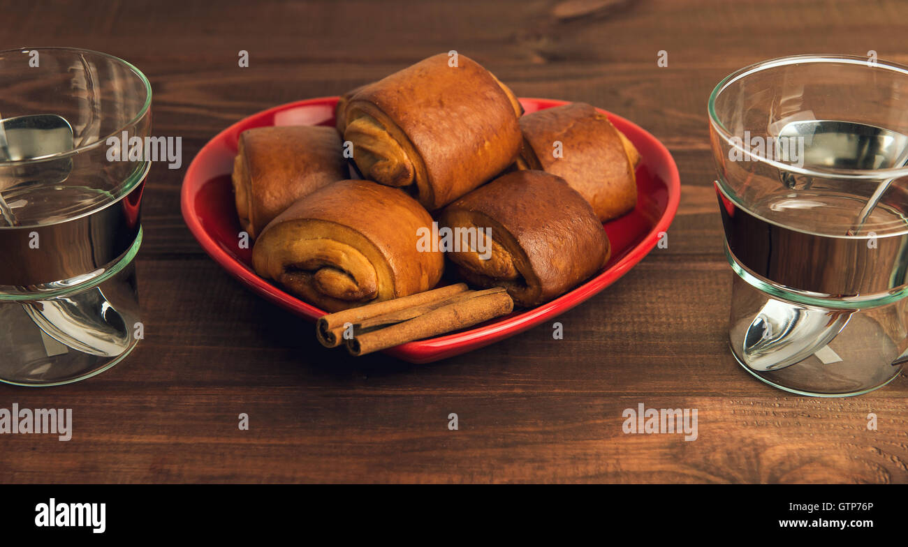 Two empty glass cups with metal handles and cinnamon rolls on a plate ...