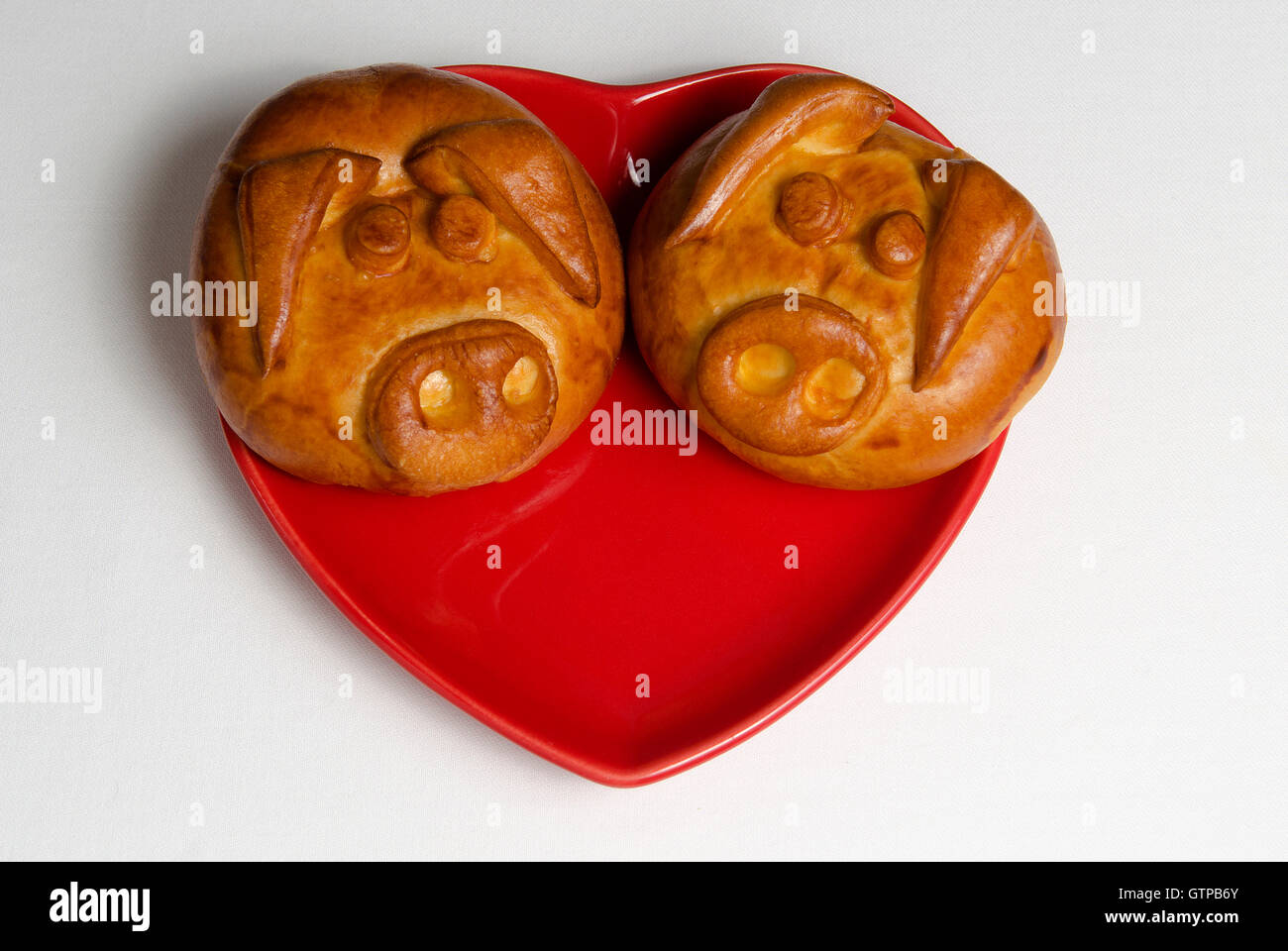 Two pigs of bread in a red heart-shaped plate Stock Photo - Alamy