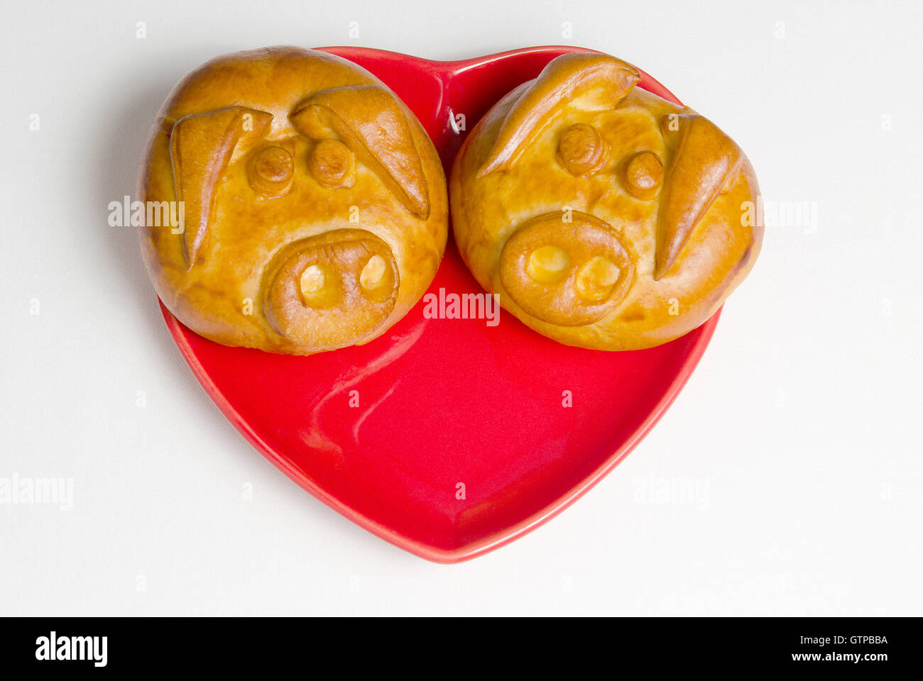 Two pigs of bread in a red heart-shaped plate Stock Photo - Alamy