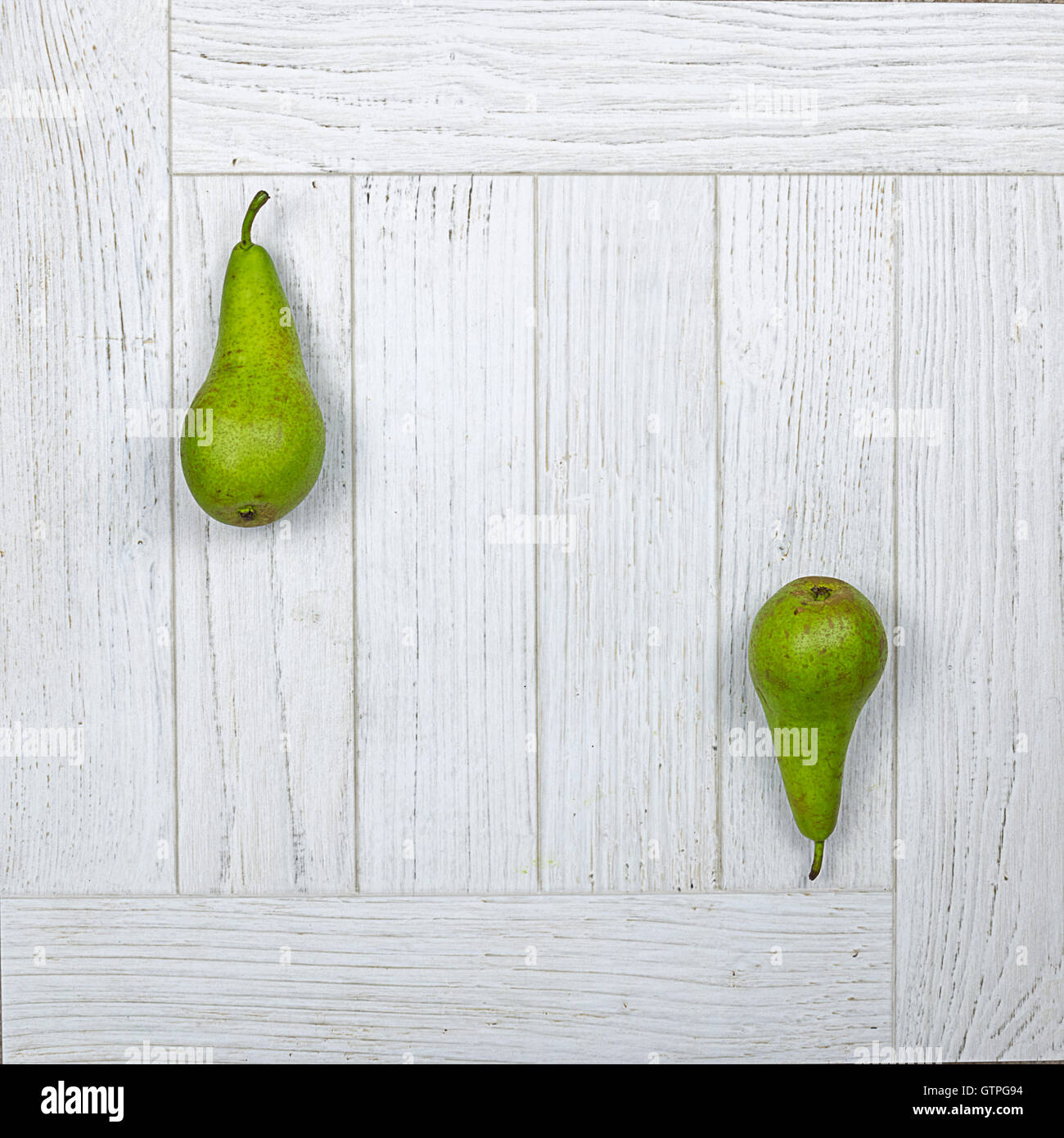Two whole conference pears on a white wooden background Stock Photo - Alamy
