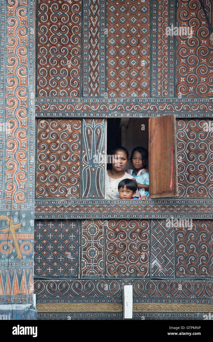 Toraja family pose for camera at the window of Toraja traditional house ...