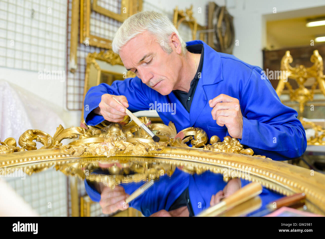 Man restoring gilt mirror Stock Photo - Alamy