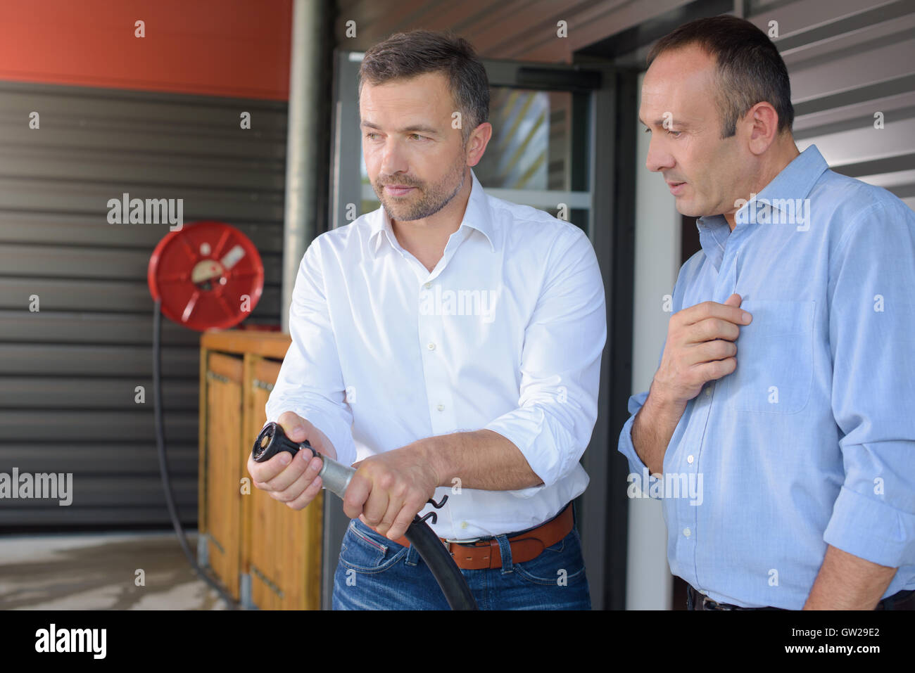 Two men turning on hose pipe Stock Photo - Alamy