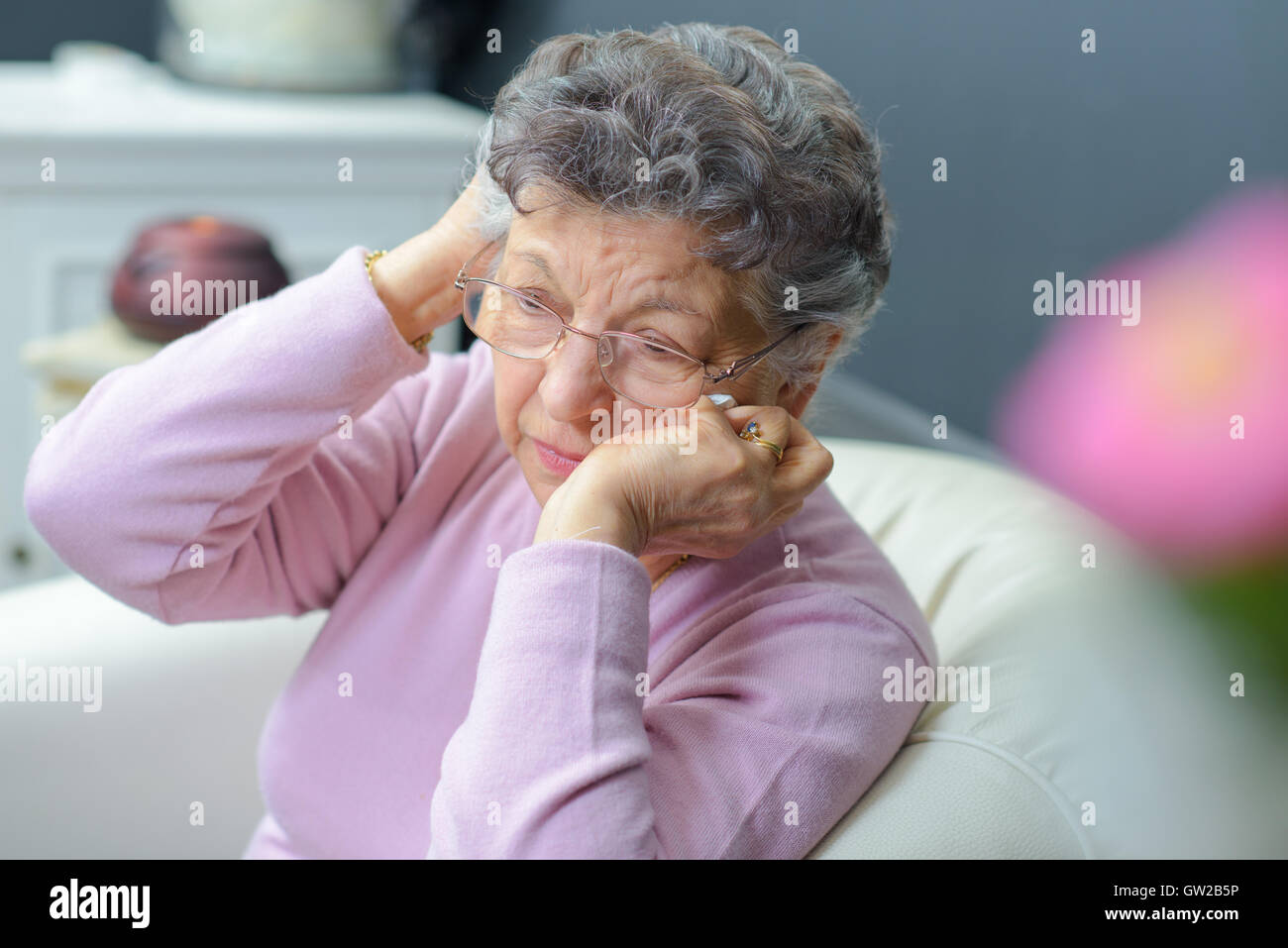 Elderly lady holding her head in her hands Stock Photo - Alamy