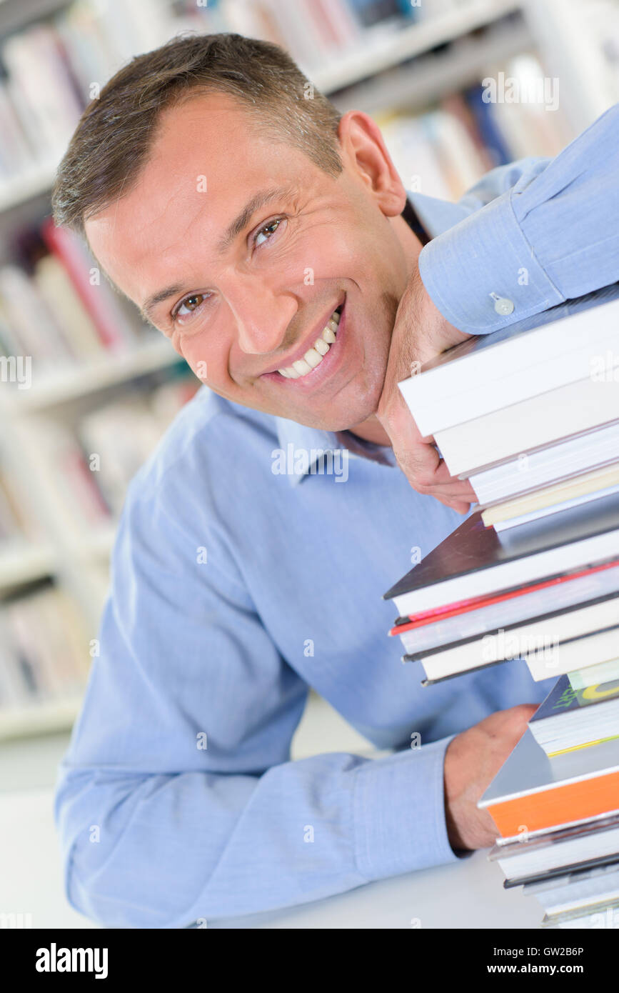 Portrait of man leaning on stack of books Stock Photo - Alamy
