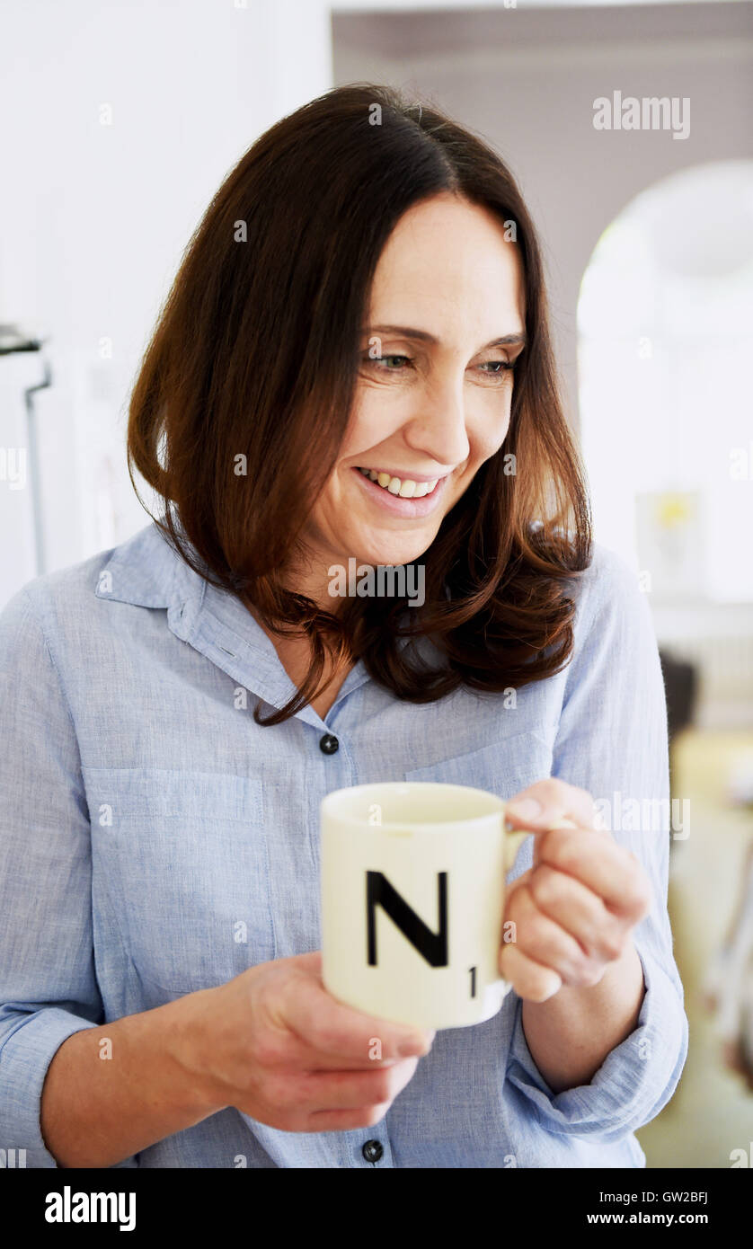 Young woman drinking coffee in her kitchen at home Stock Photo - Alamy