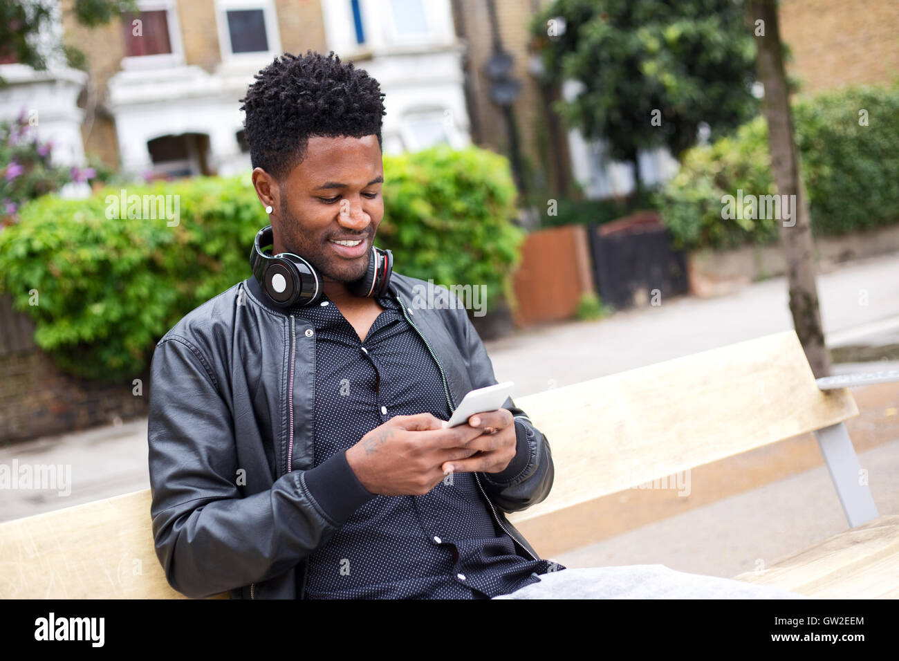 young man reading his text messages sat on a bench in the street Stock ...