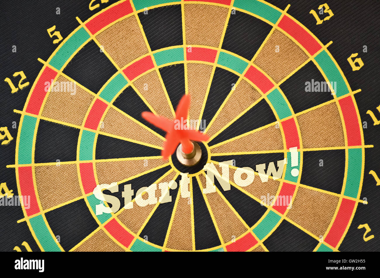 Text Start Now written on the circular target with a plastic feather in ...