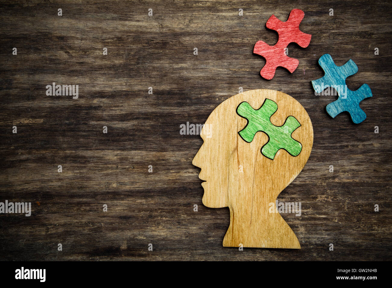 Human head silhouette with a jigsaw piece cut out on the wooden ...