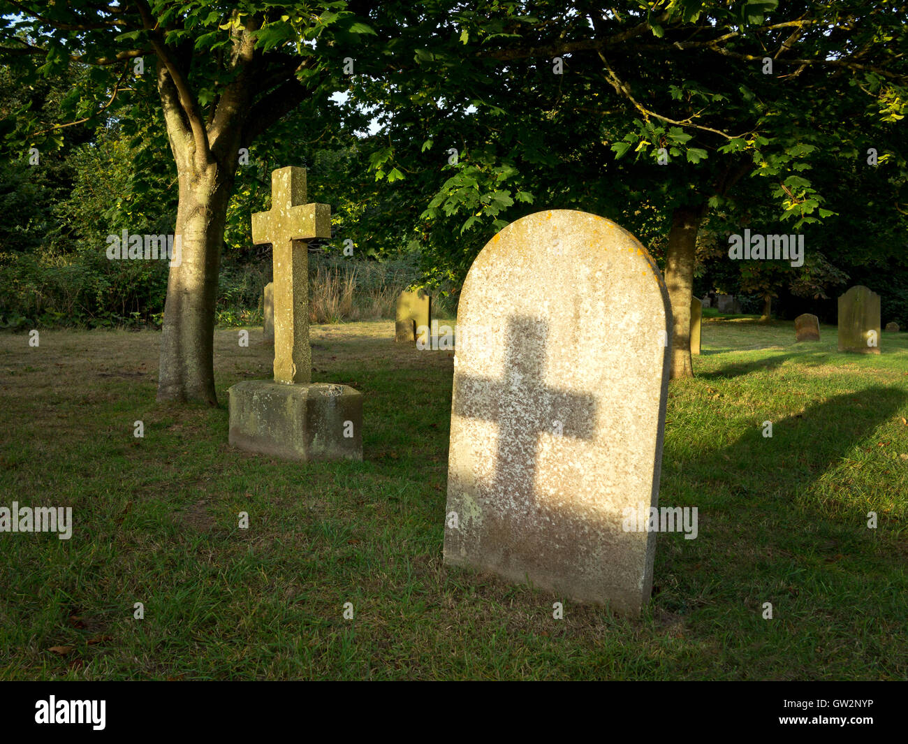A rounded top gravestone back with the shadow of a cross headstone on ...